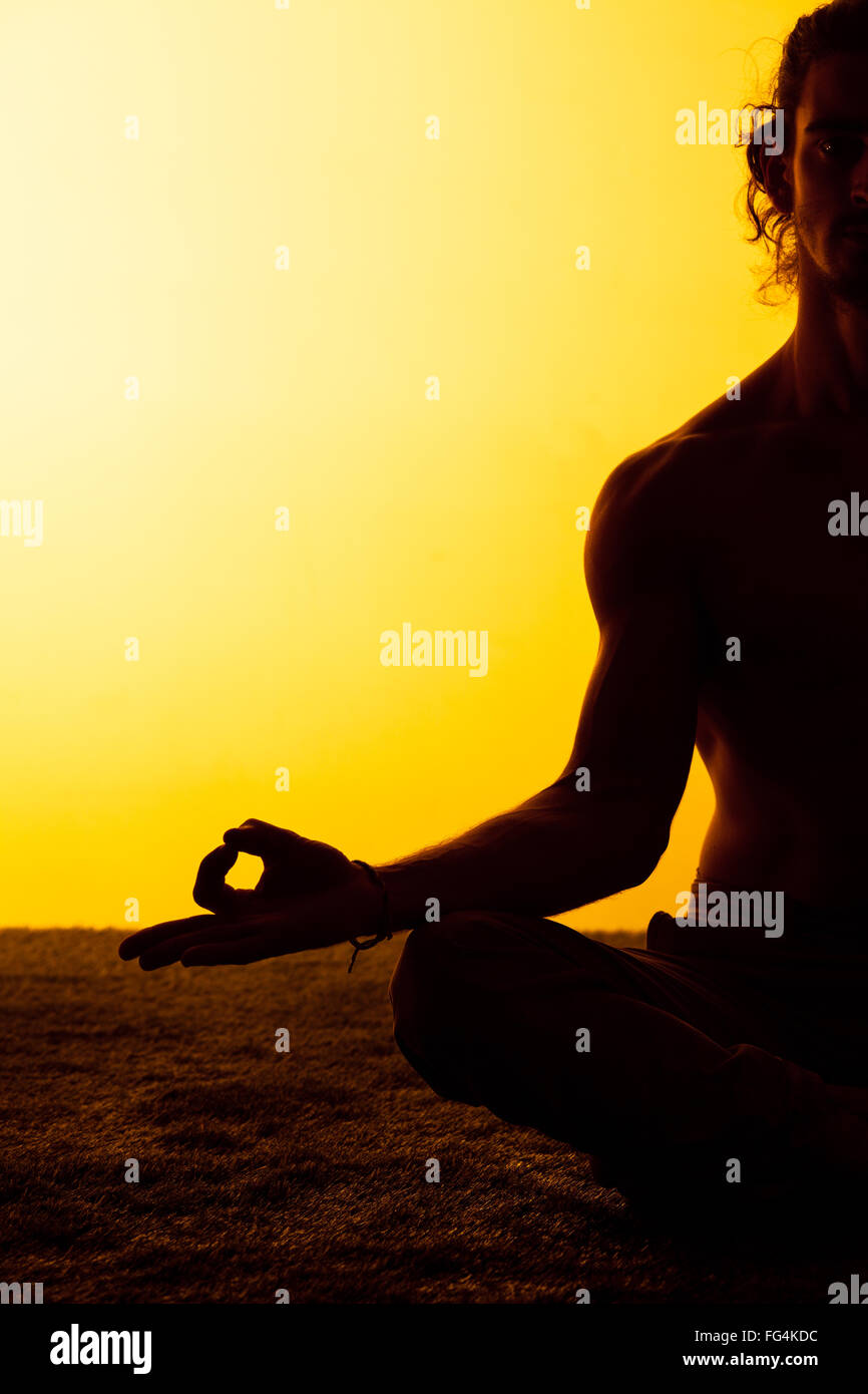The man practicing yoga in the sunset light Stock Photo - Alamy