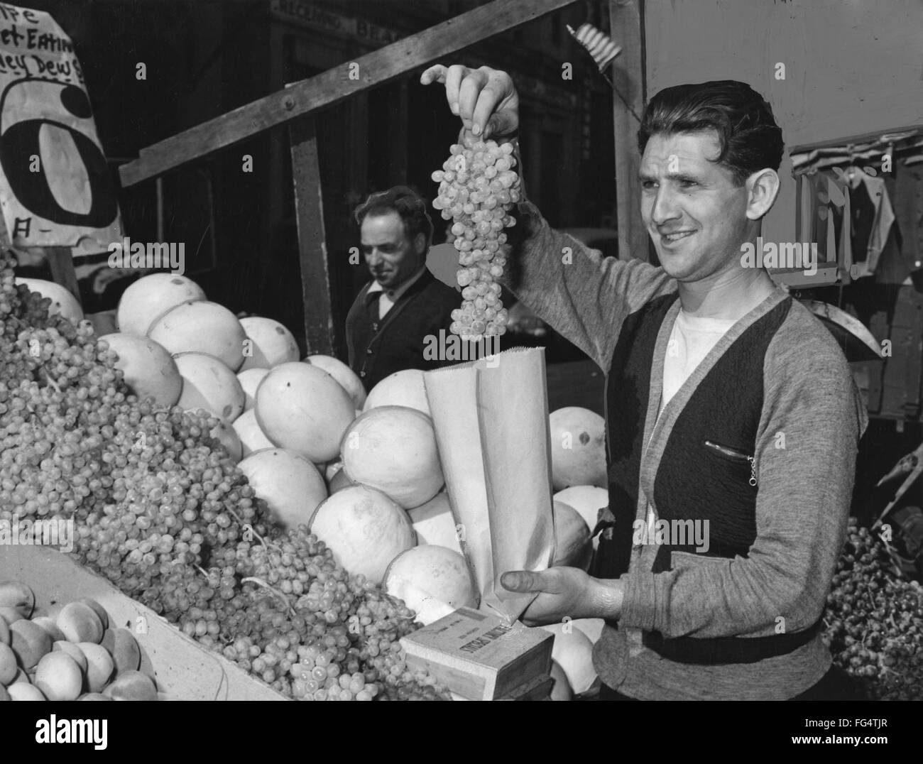 BROOKLYN: VENDOR, 1940. /nPushcart vendor Al Rabinowitz bagging grapes ...