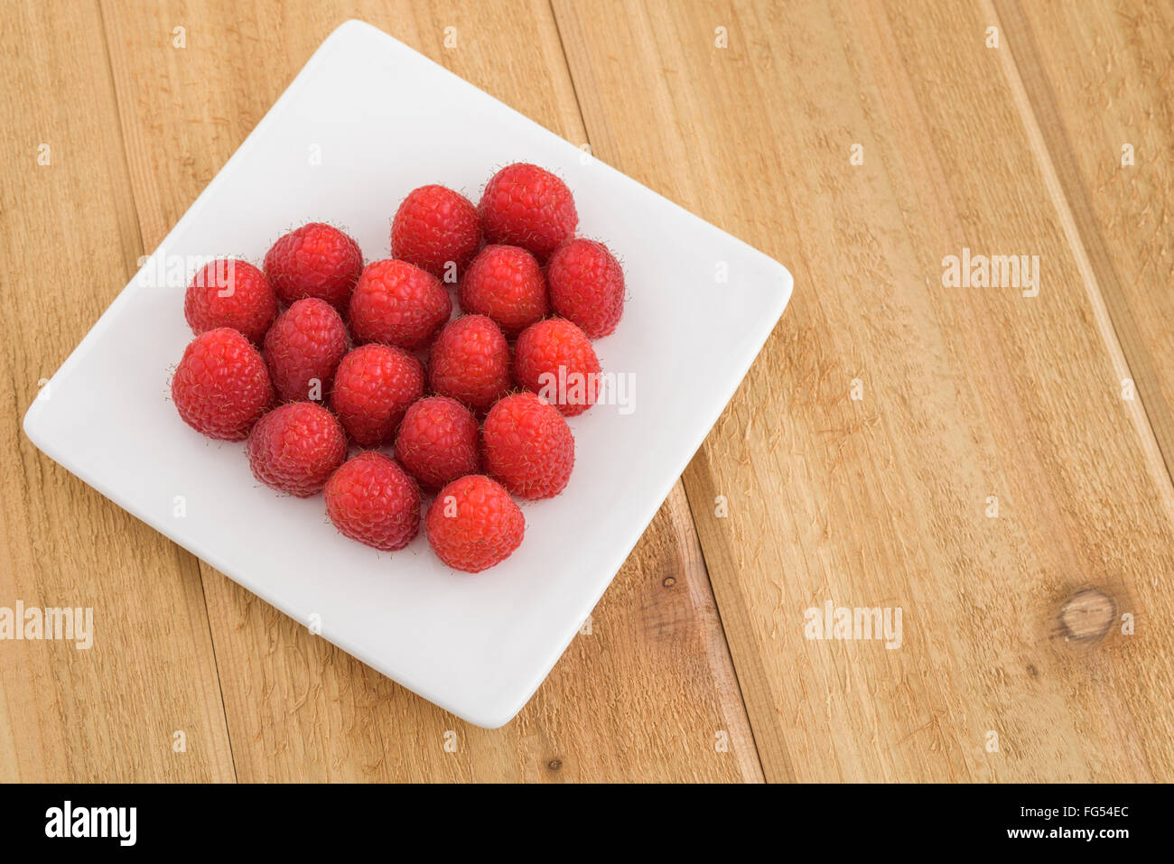 Fresh red raspberries in a heart shape on a white plate, cedar ...