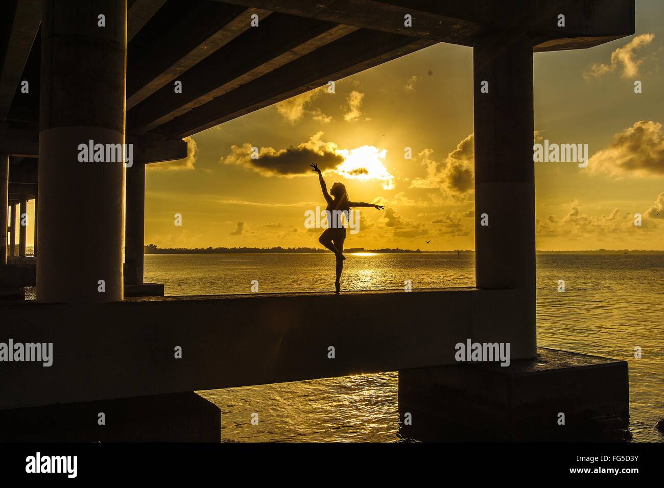 Woman Dancing Under Bridge At River During Sunset Stock Photo - Alamy