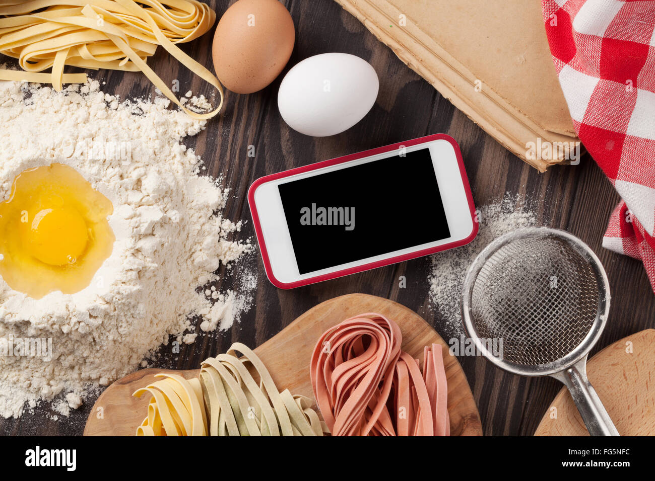 Kitchen table with blank screen smartphone, utensils and ingredients ...