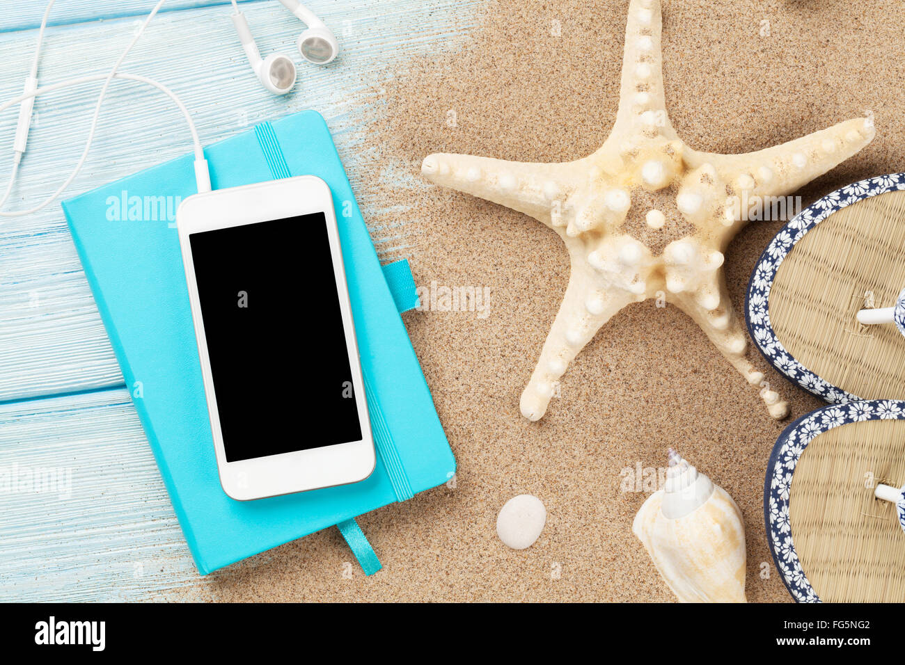 Smartphone and notepad on wooden table with starfish and shells. Top ...