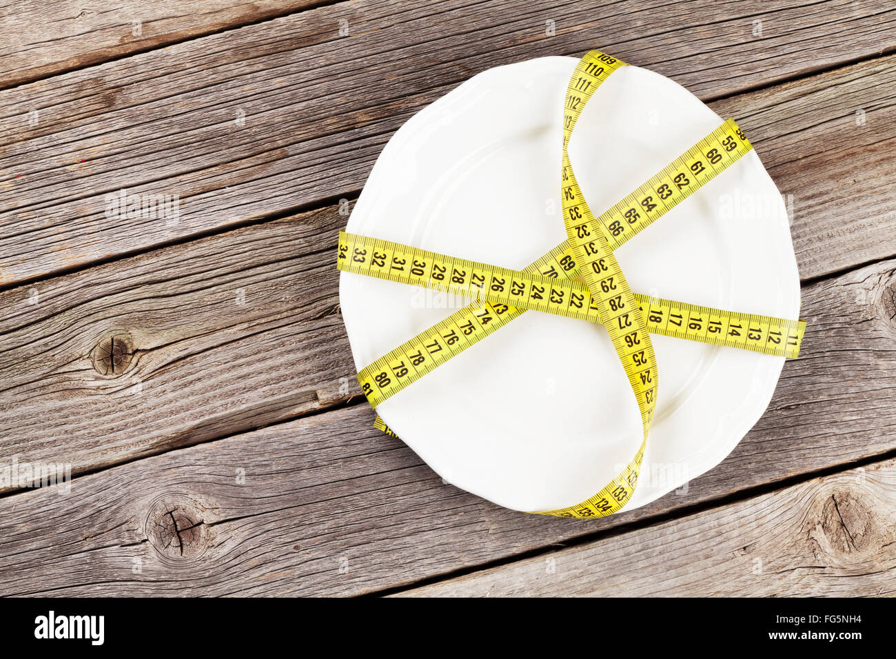Healthy food concept. Plate and tape measure on wooden table. Top view ...