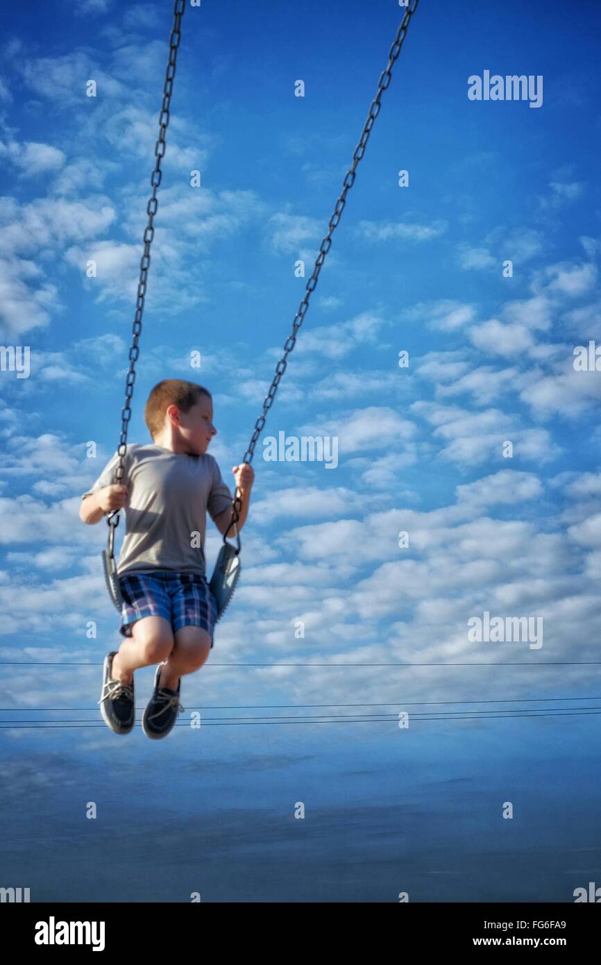 Boy Swinging Against Cloudy Blue Sky Stock Photo - Alamy