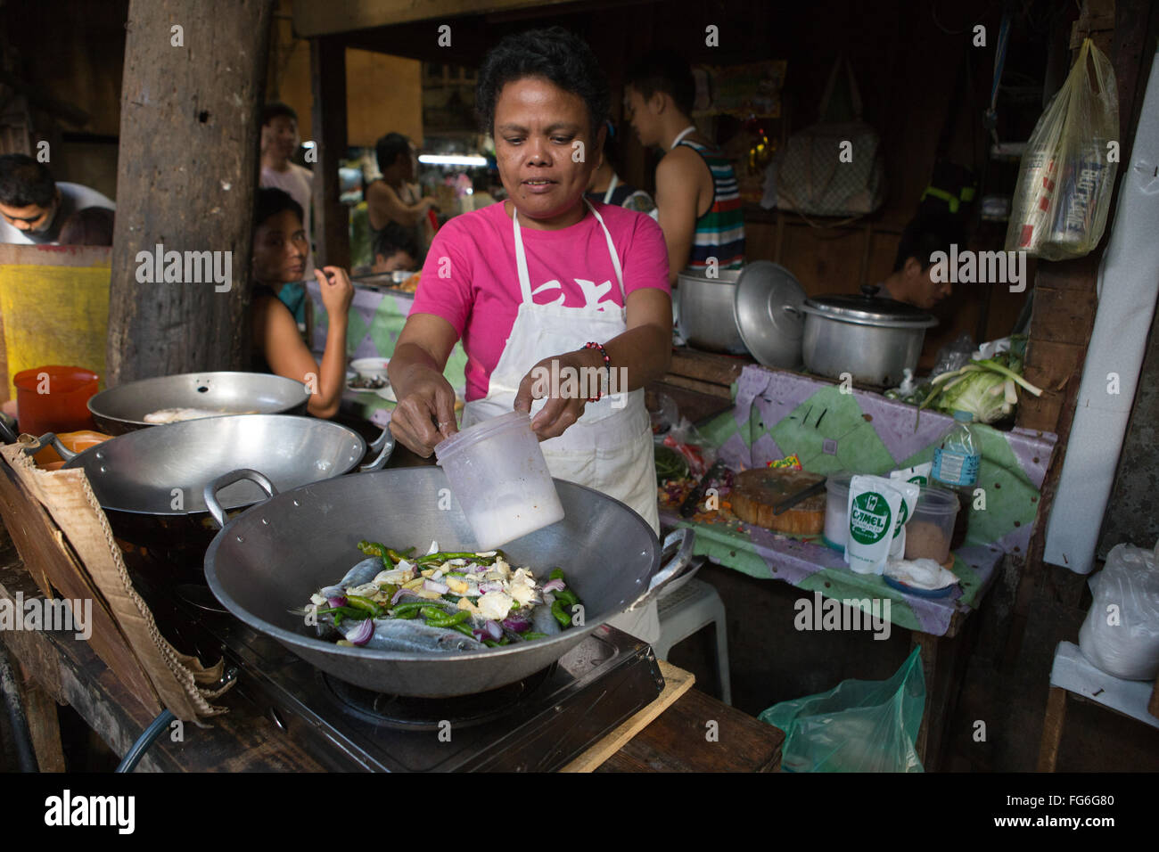 A Filipino woman cooking a local fish delicacy within the Carbon Market ...
