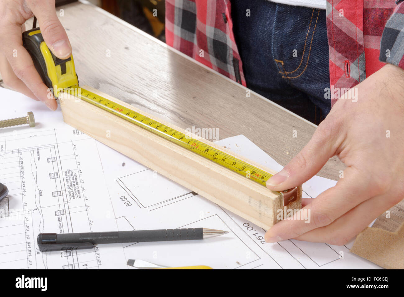 a young man measuring wooden board Stock Photo - Alamy