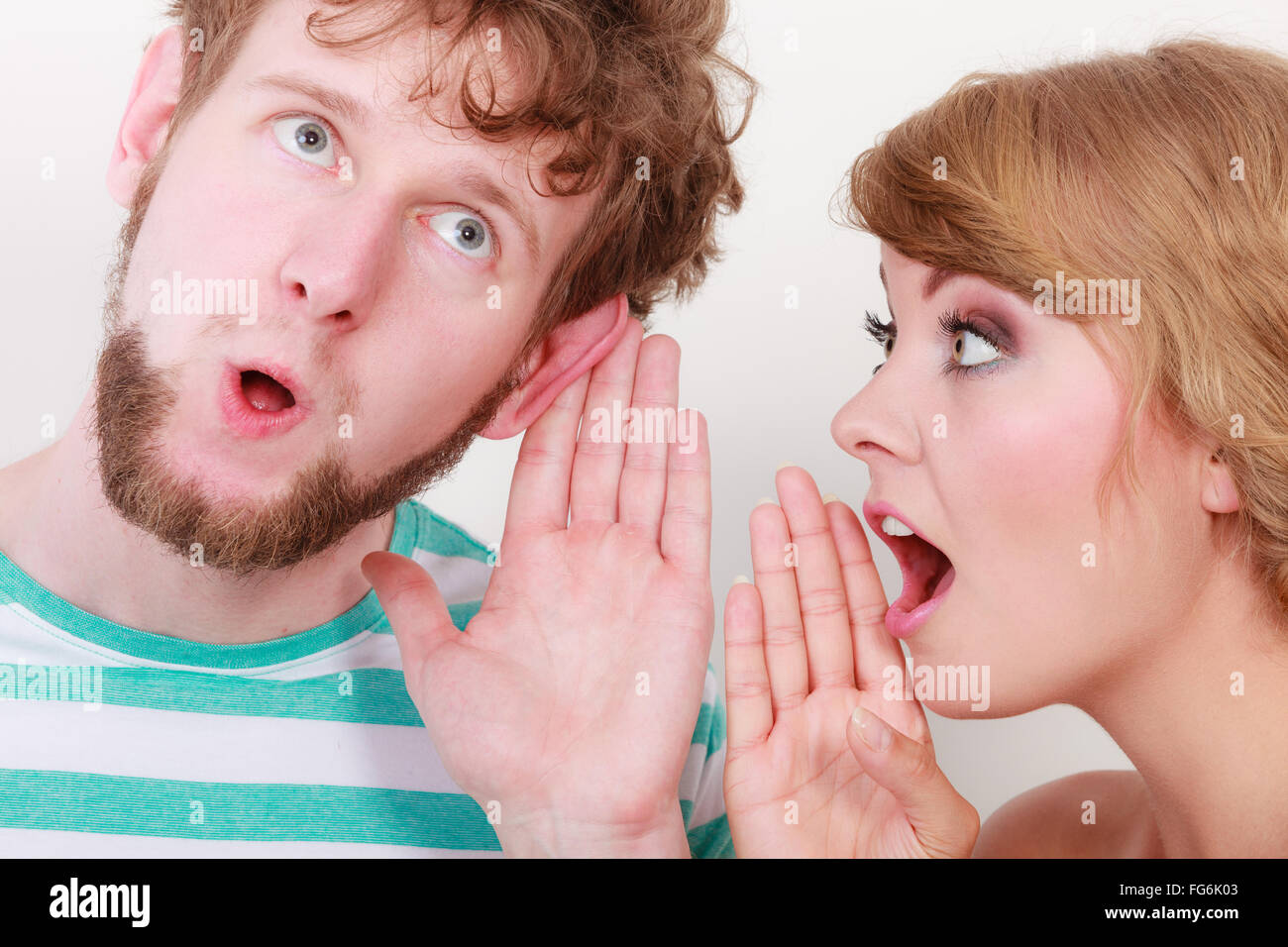 Closeup woman telling an astonished surprised man some secrets, couple ...