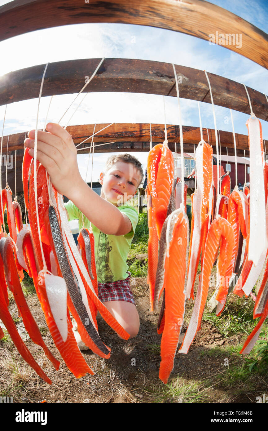 Boy looking at drying rack of salmon at fish camp in Bristol Bay ...