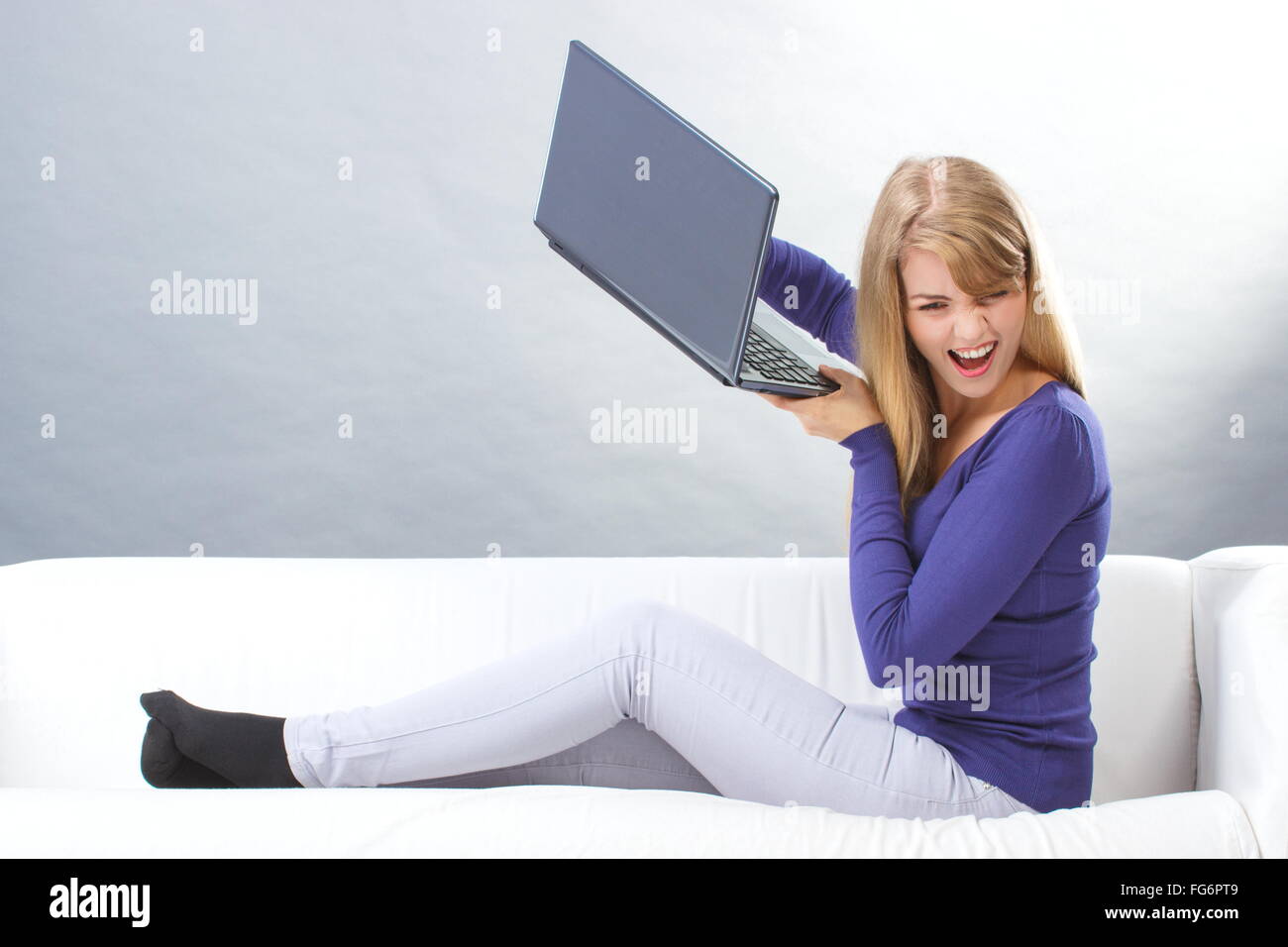 Angry woman sitting on sofa and throwing her laptop, computer or ...