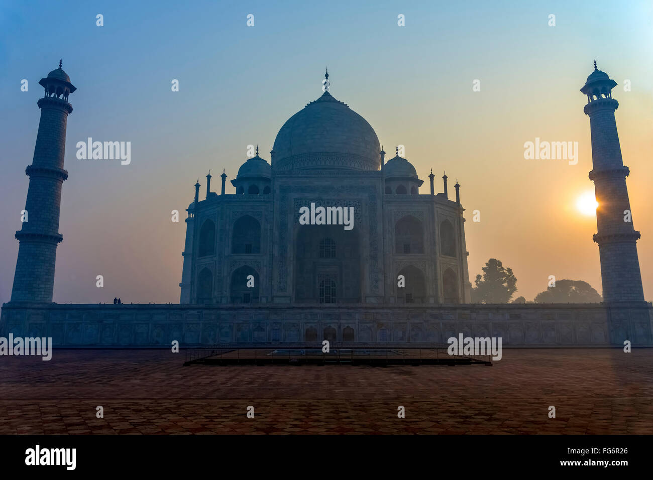 Sun rising behind one of the minarets of the Taj Mahal without a cloud ...