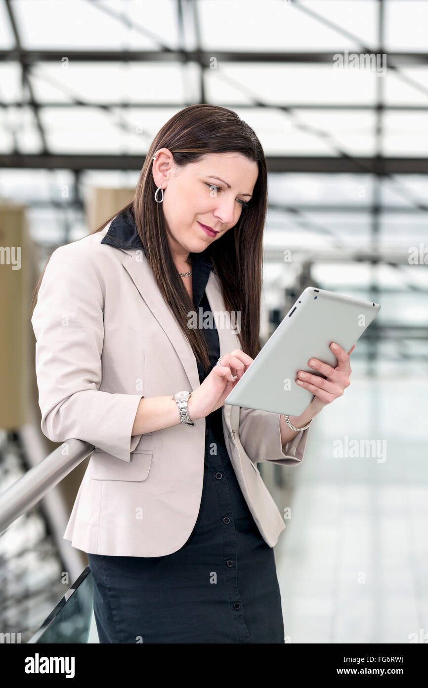Mature business woman using her touch screen in an atrium; Edmonton ...