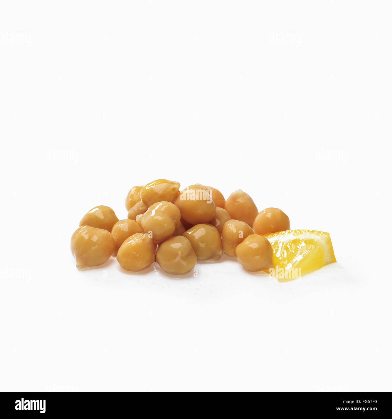 Chick peas and a piece of lemon on a white background; Toronto, Ontario ...