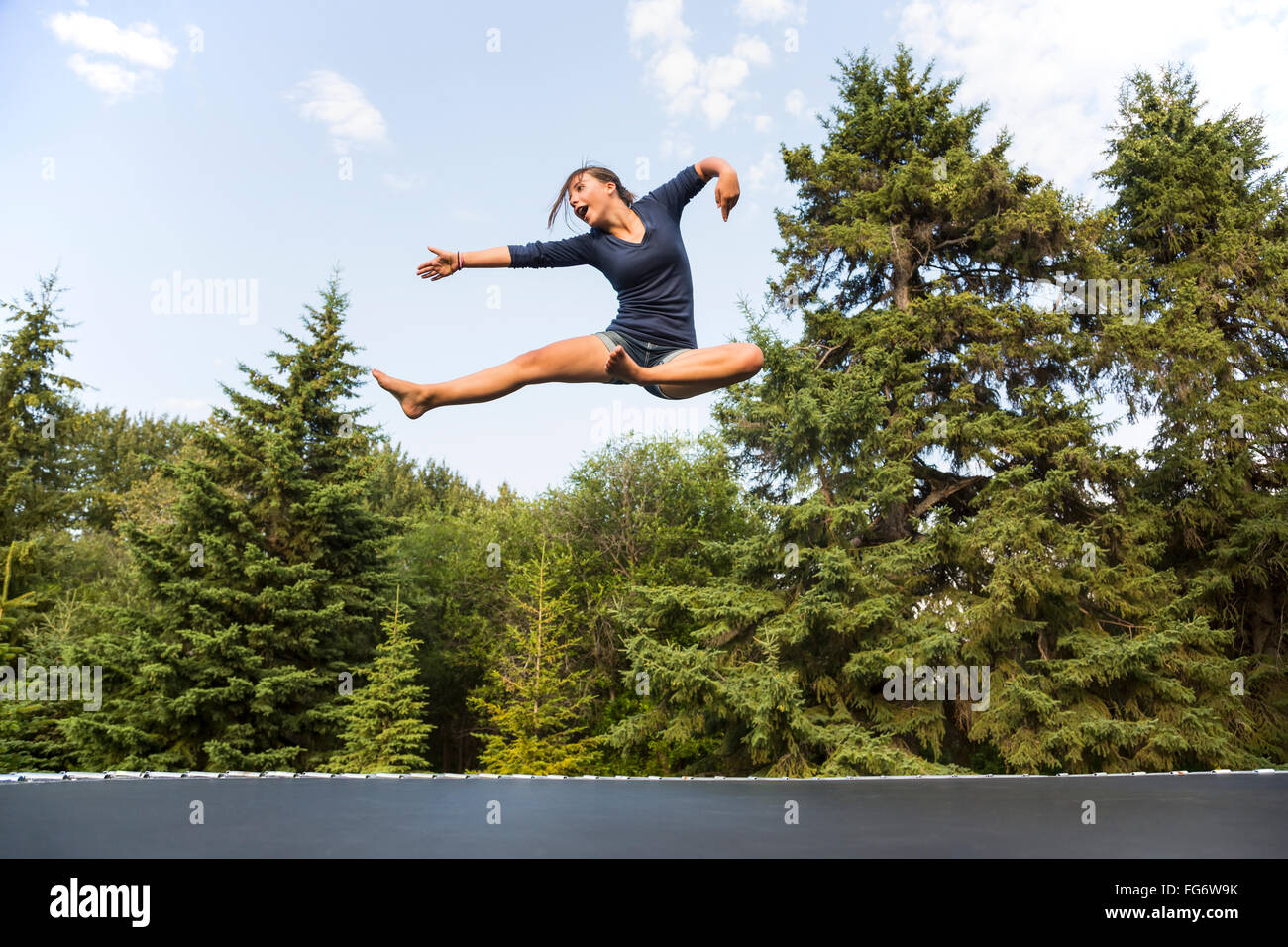 Teenage girl jumping high in the air outdoors on a trampoline; Sherwood ...