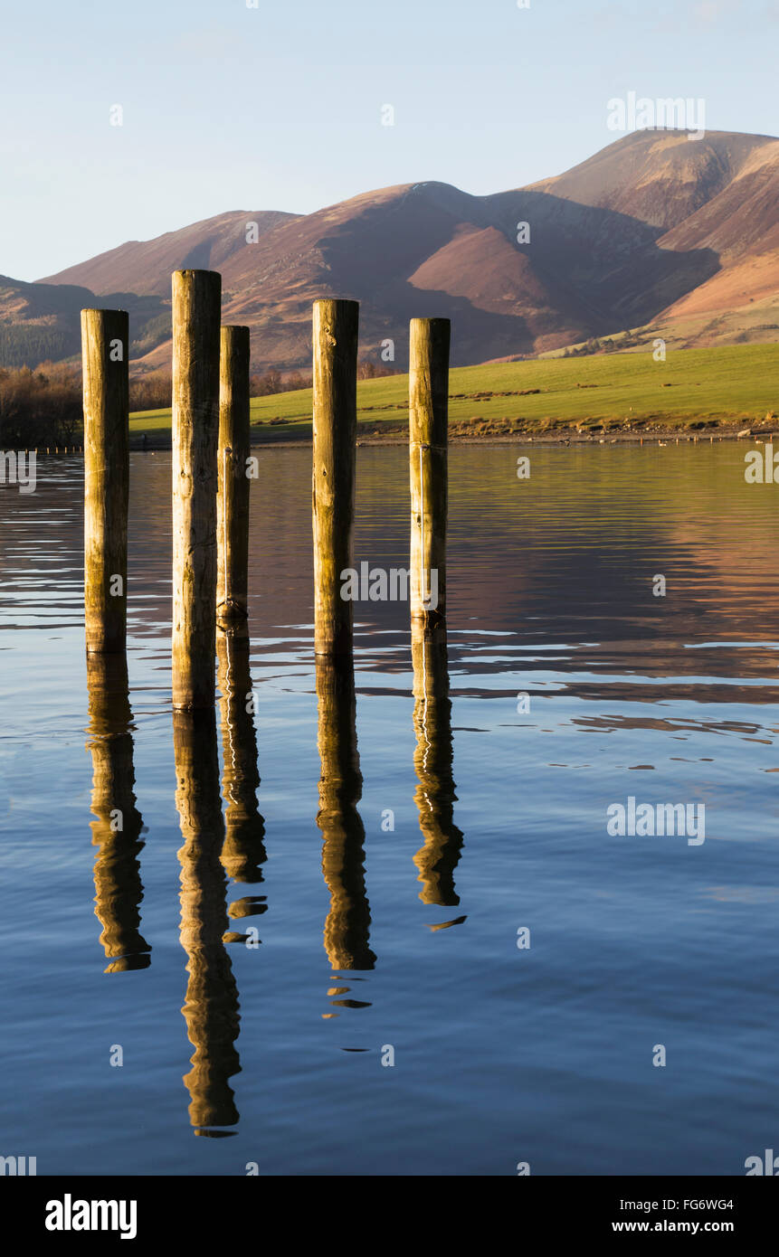 Wooden posts reflected in tranquil after with mountains the the ...