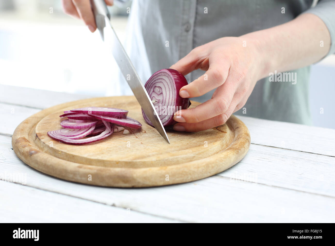 Cutting the onion into slices. Woman cut red onion on the kitchen ...