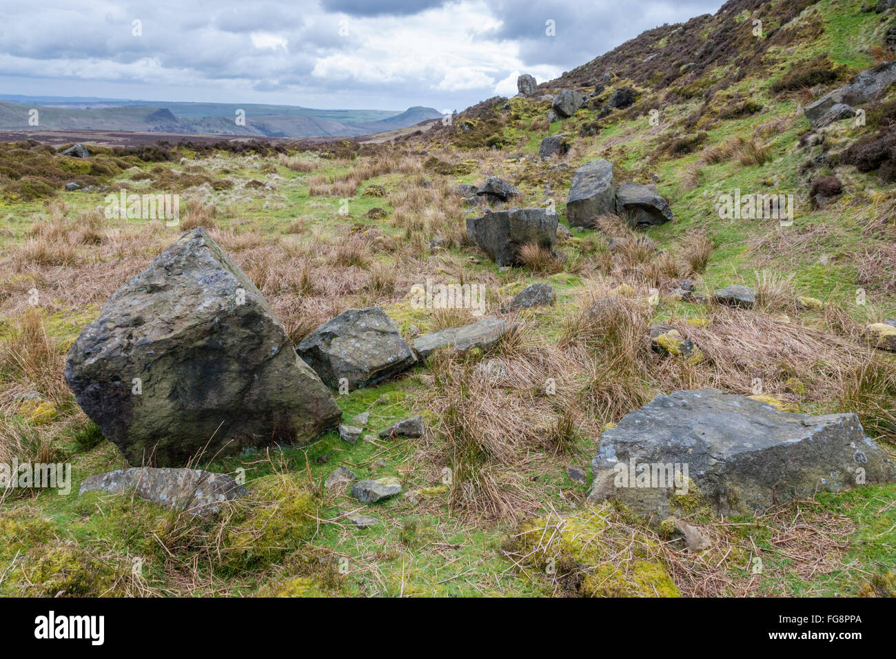 Gritstone rocks and boulders at the foot of a moorland hill at ...