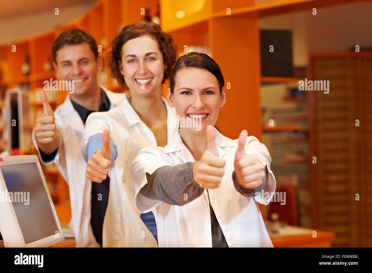 Three happy pharmacists holding their thumbs up in pharmacy Stock Photo ...