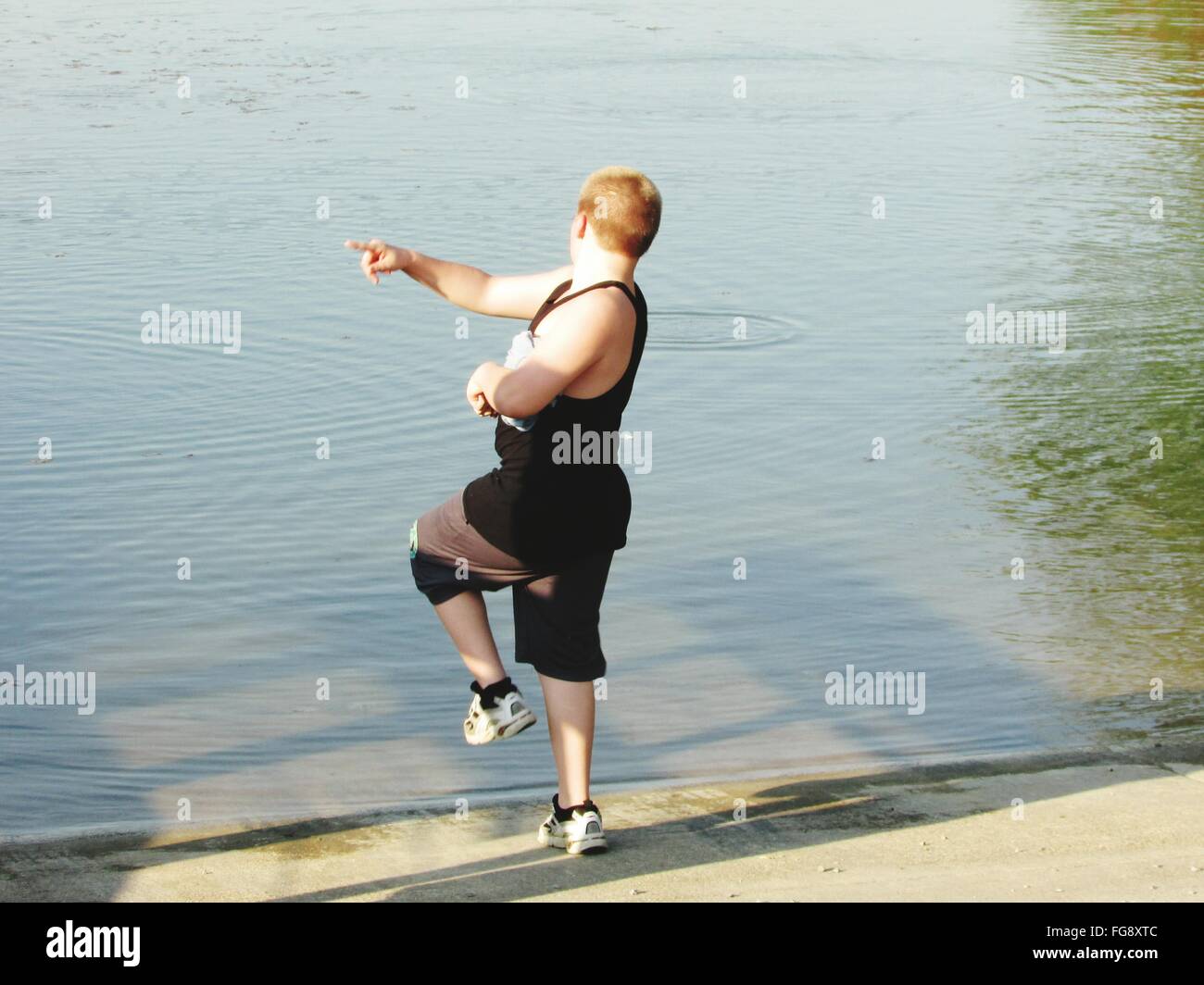 Rear View Of Boy Throwing Stone In Lake Stock Photo - Alamy