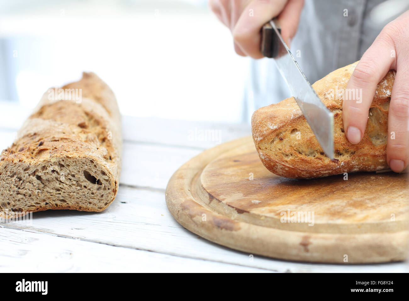Woman hands cutting bread on the kitchen counter. baguette. Slicing ...