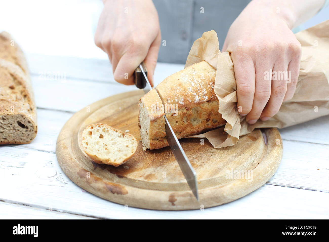 Woman hands cutting bread on the kitchen counter. baguette. Slicing ...