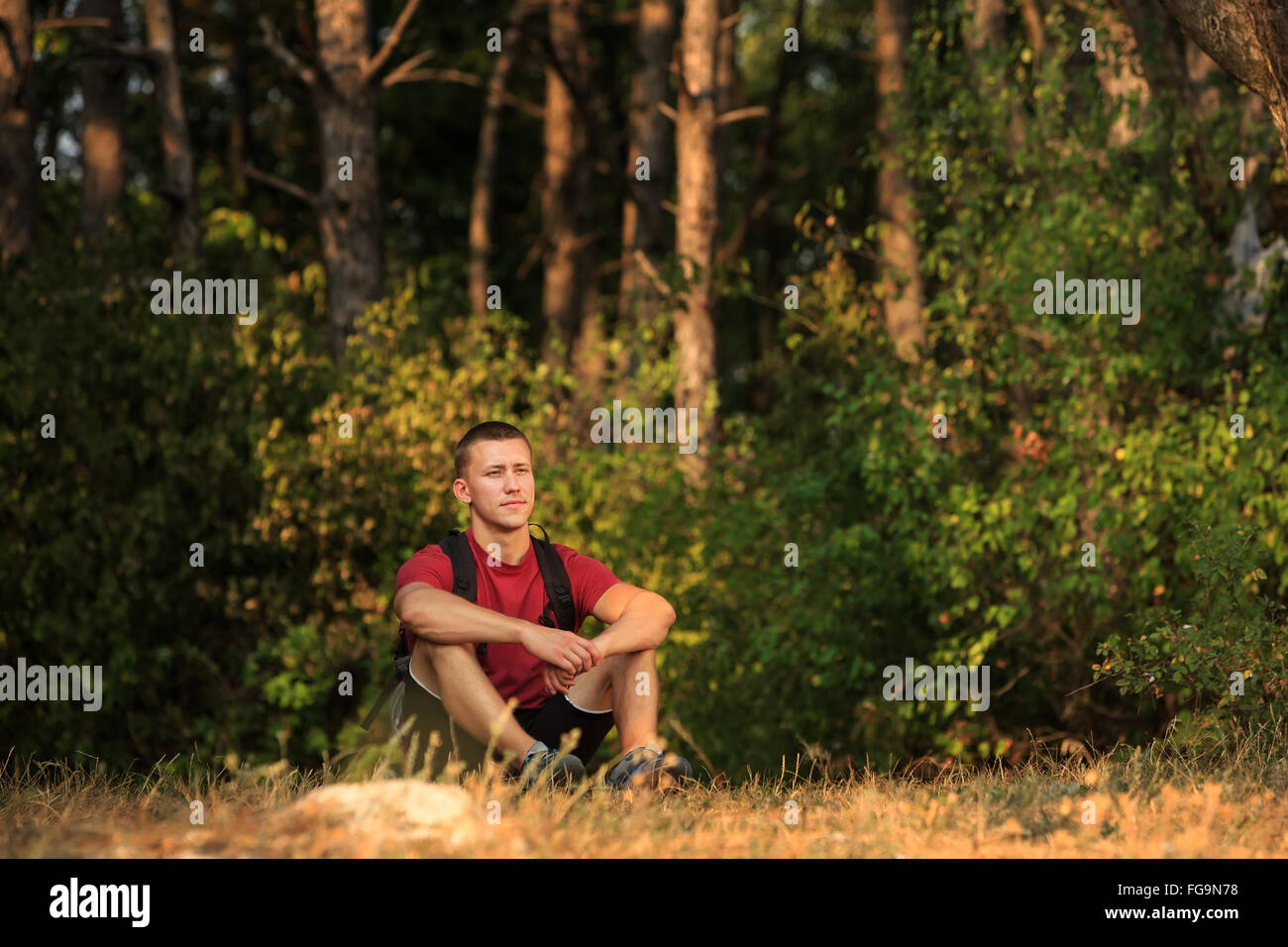 Happy hiker man sitting on the ground and looking forward Stock Photo ...