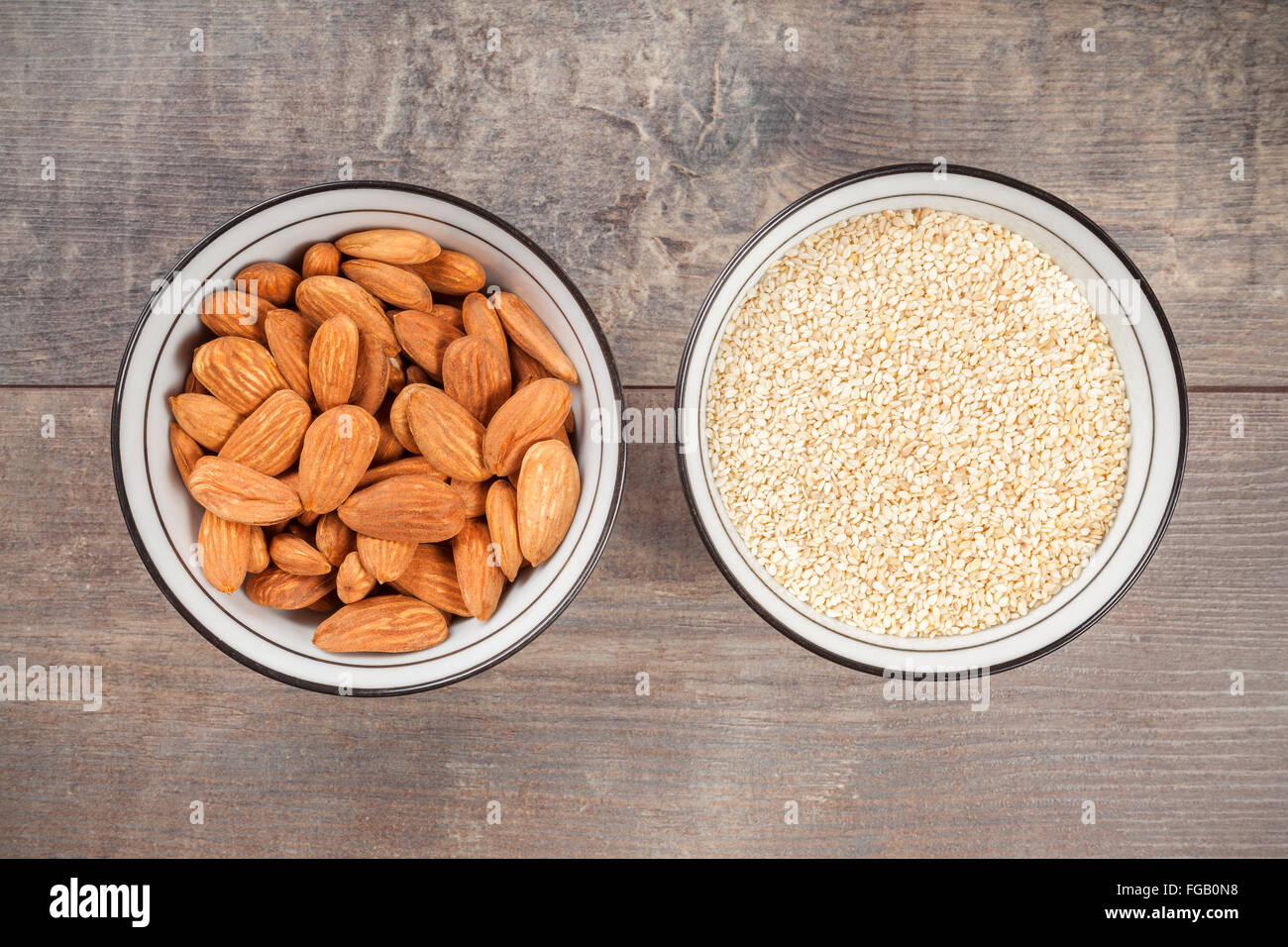Almonds and sesame seeds in bowls on wooden background Stock Photo - Alamy