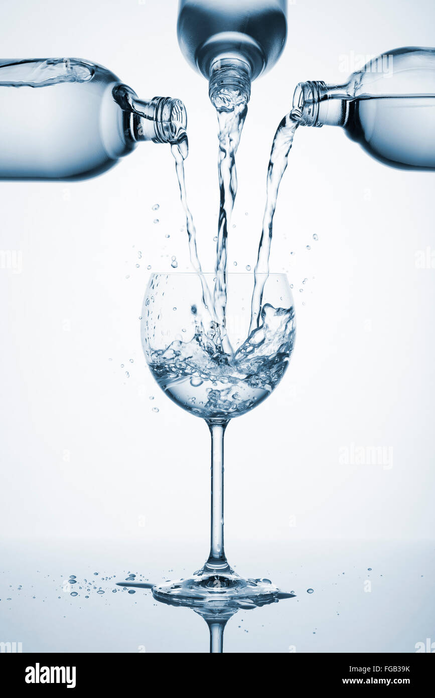 three bottles pouring water in glass with splashes, with blue light Stock Photo - Alamy