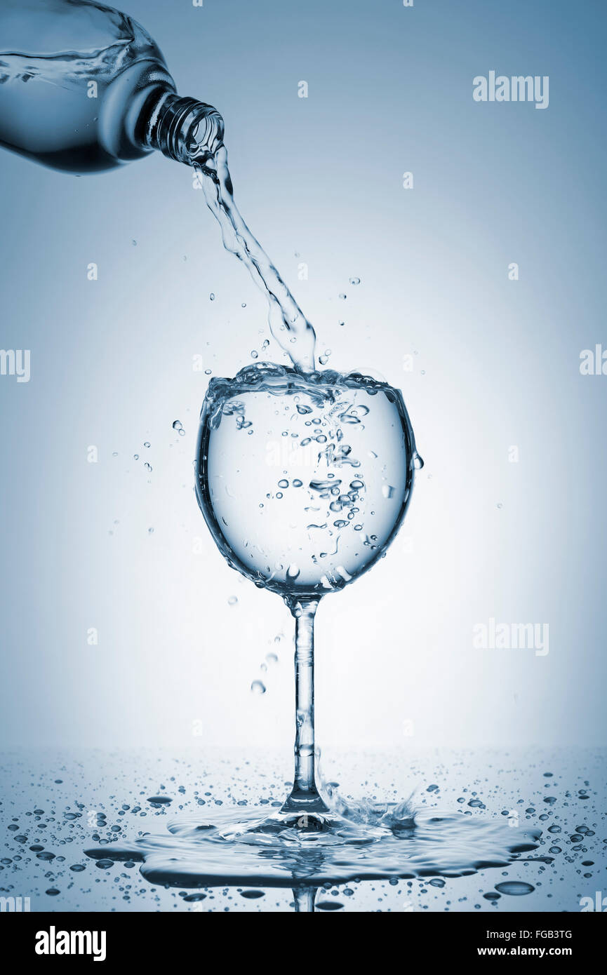 bottle pouring water in glass with splashes, on blue background Stock Photo - Alamy