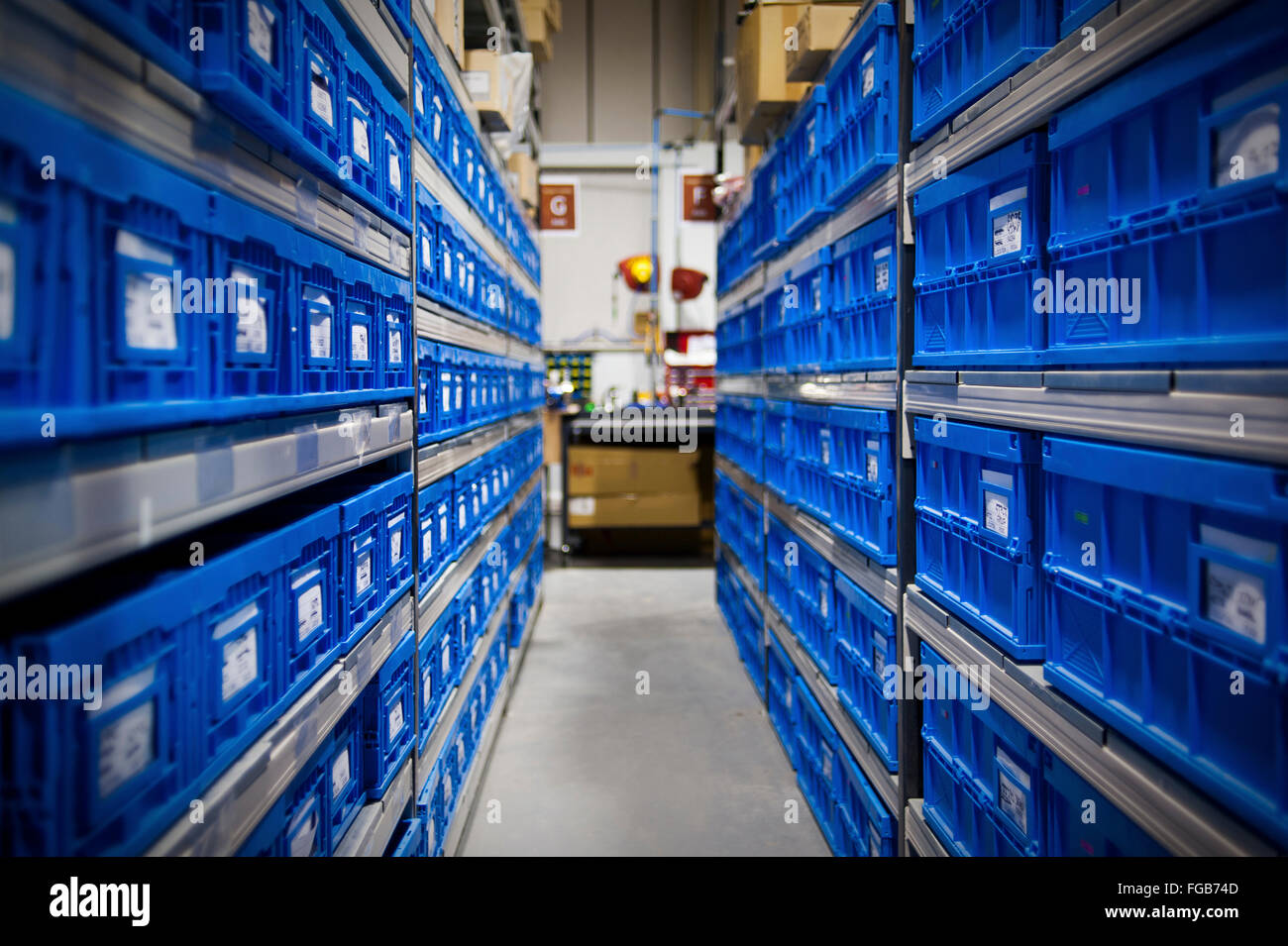 Corridor between shelves of blue plastic parts boxes in a warehouse ...