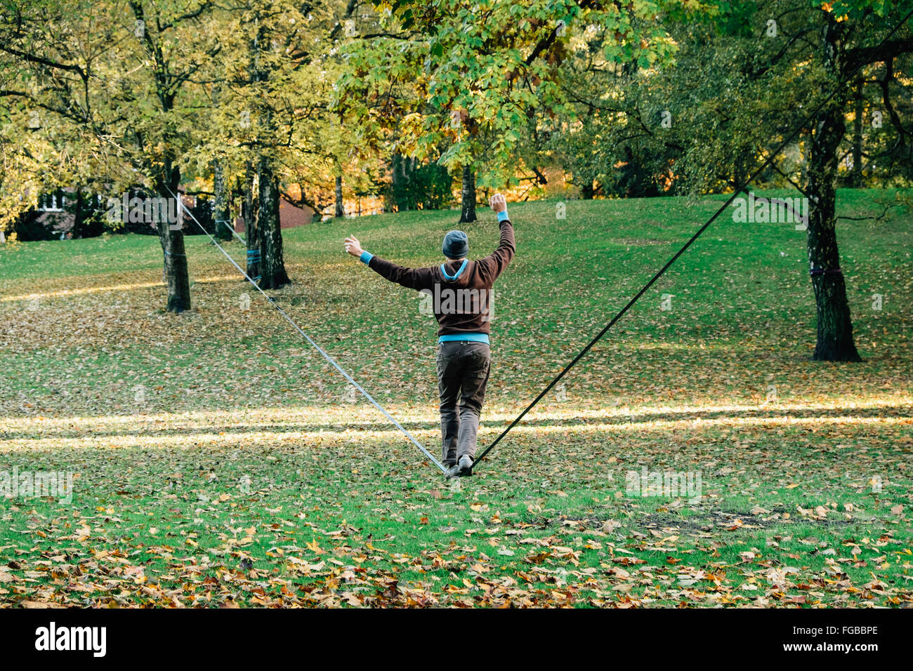 Rear View Of Man Walking On Rope At Park Stock Photo - Alamy