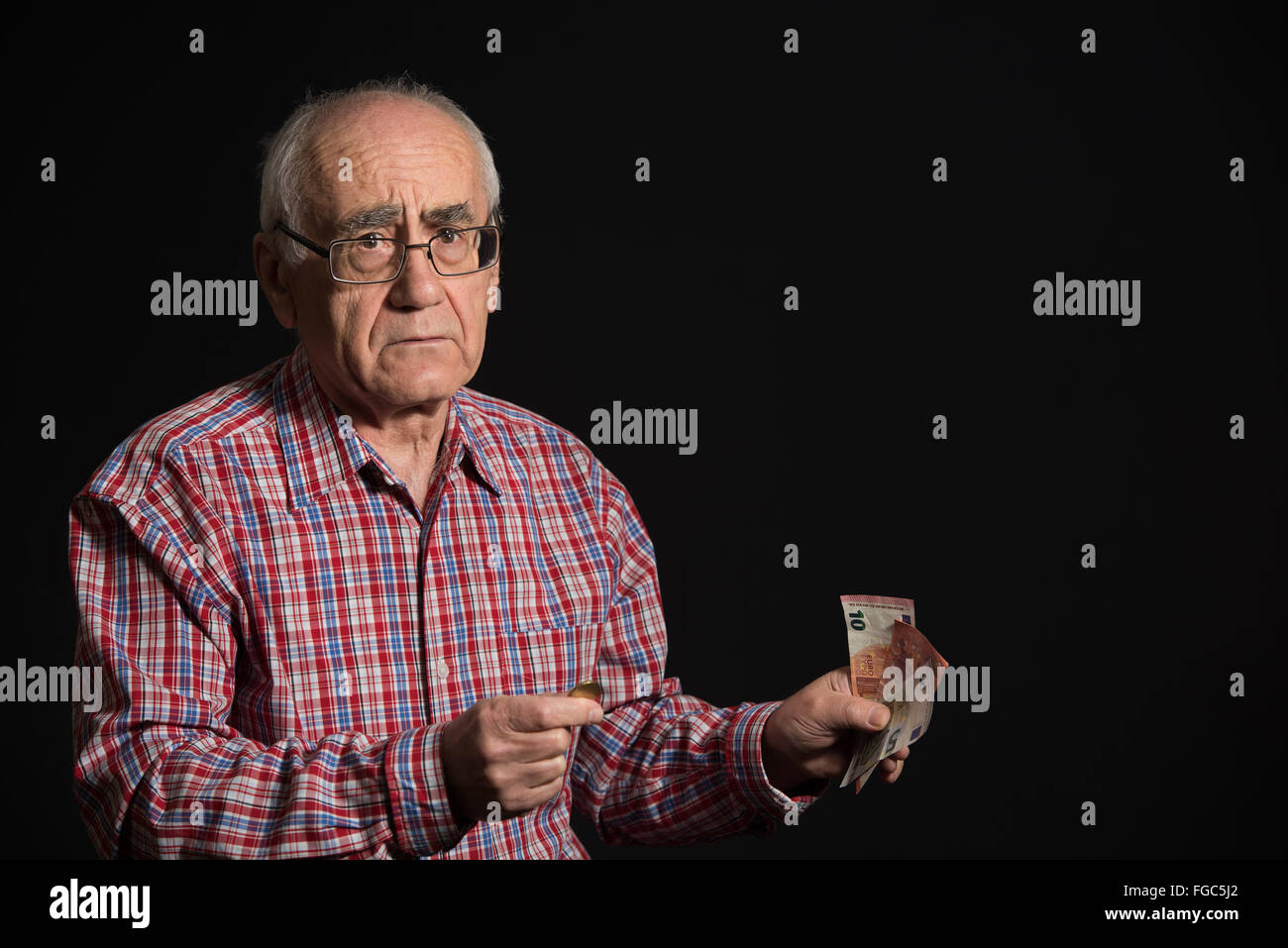 old man wearing checked shirt and eyeglasses holding euro banknotes ...