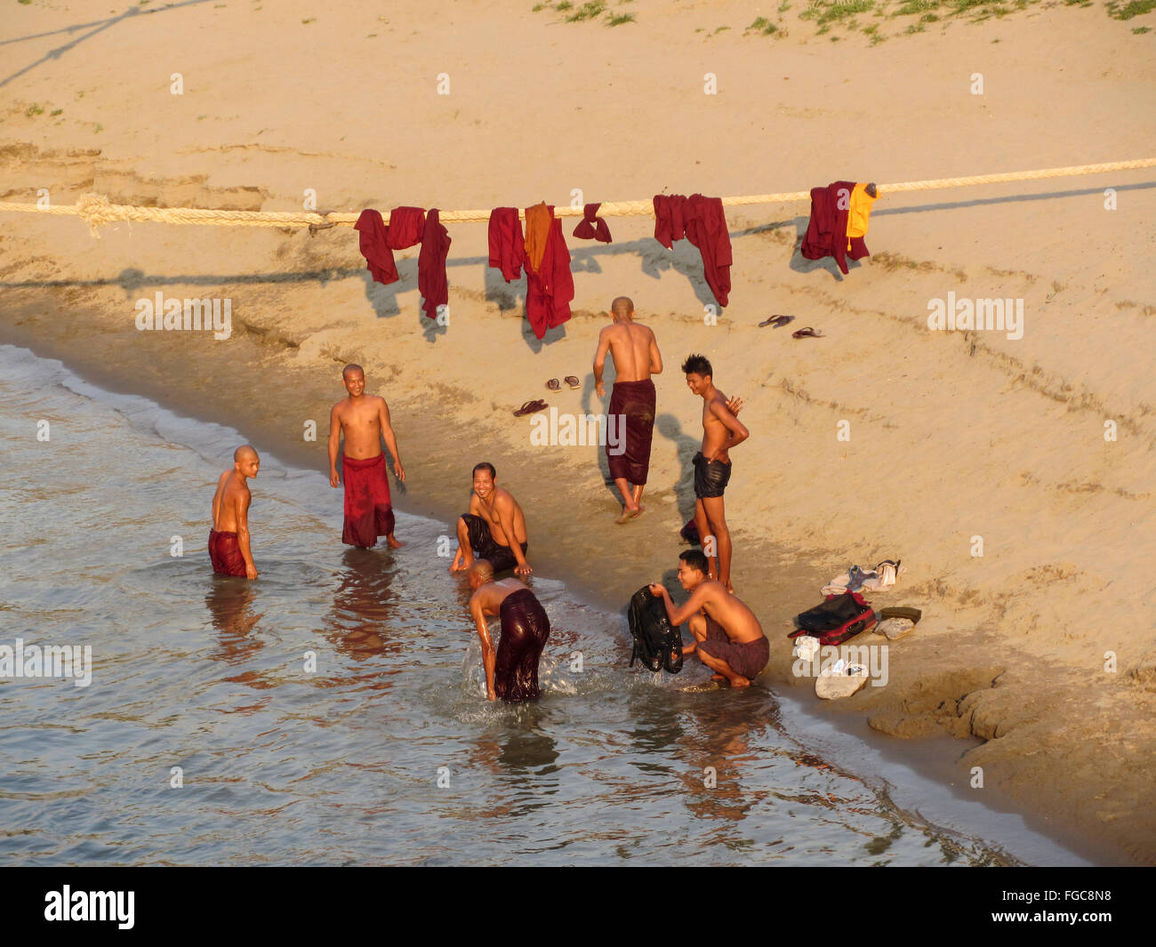 Group of adult male Buddhist monks bathing and washing their clothes on ...
