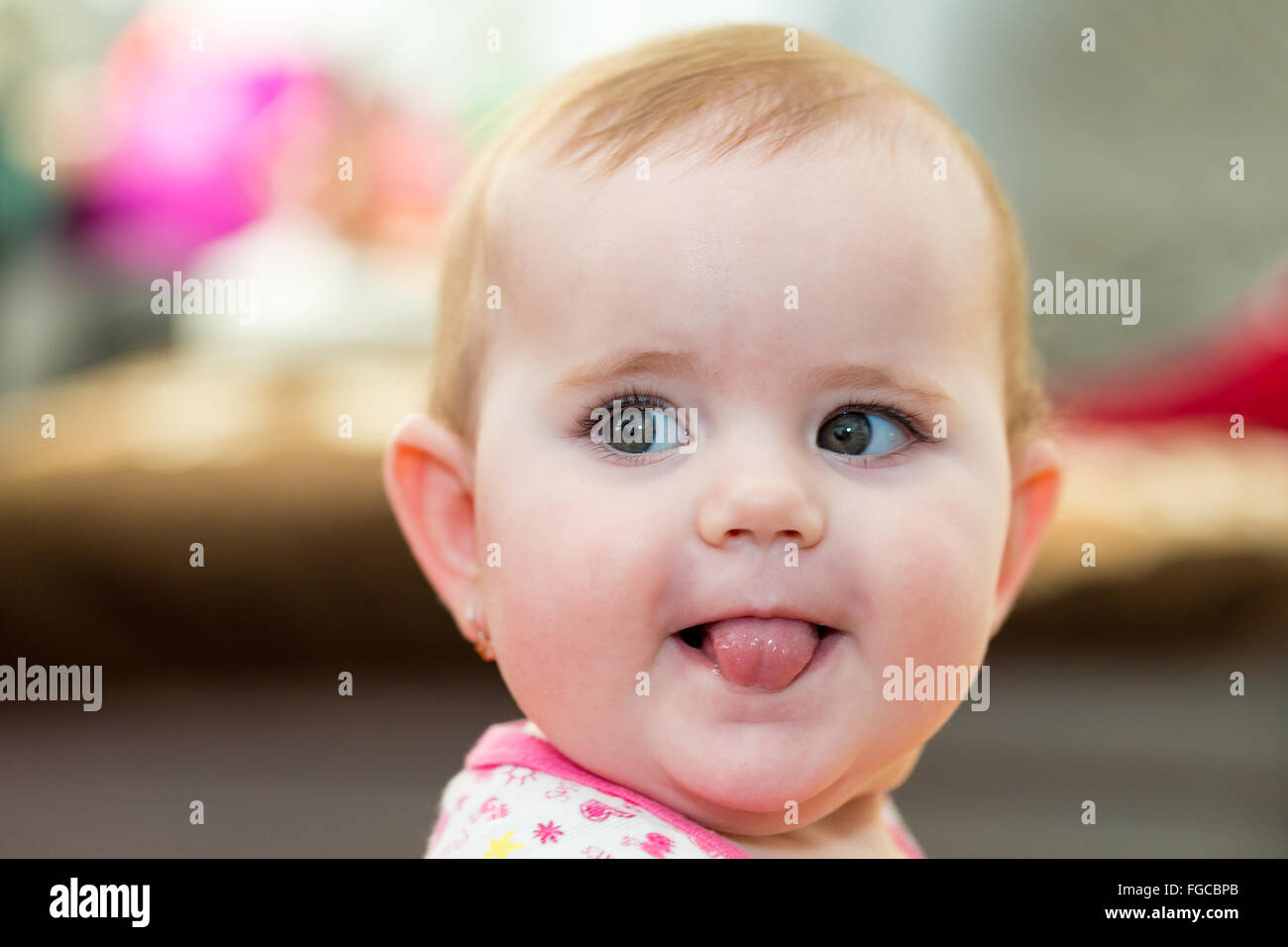 Happy cute little one year old girl indoor smiling and stick your ...