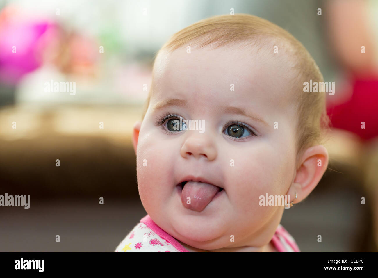 Happy cute little one year old girl indoor smiling and stick your ...