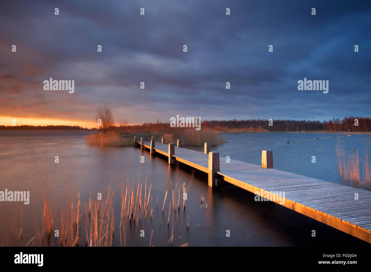 A boardwalk over a lake with an ominous sky. Photographed at sunrise ...