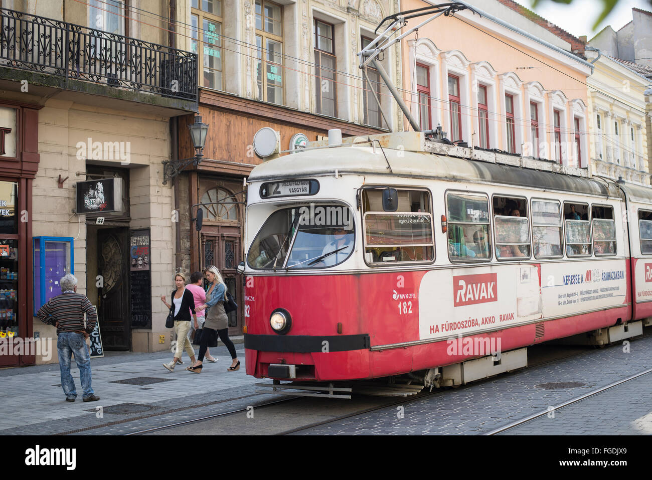 Old red tram in European town traveling on narrow street with old ...