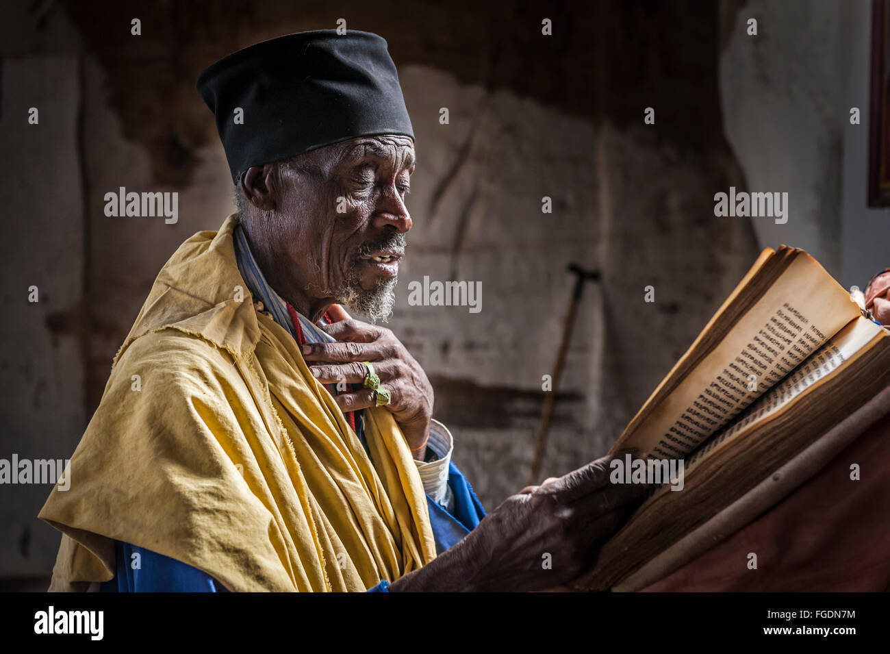 Old monk reading the Bible inside a dark church during the celebration ...