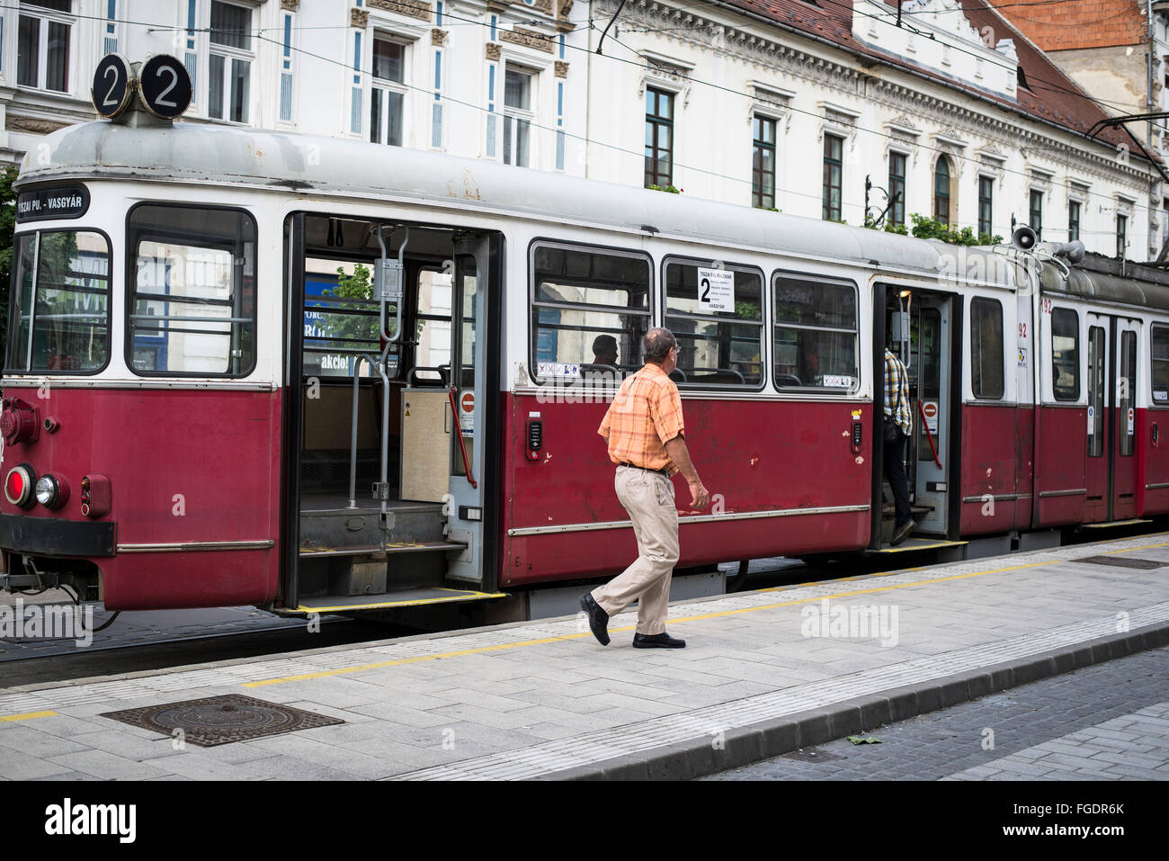 Old red tram in European town with doors open and passengers going out ...