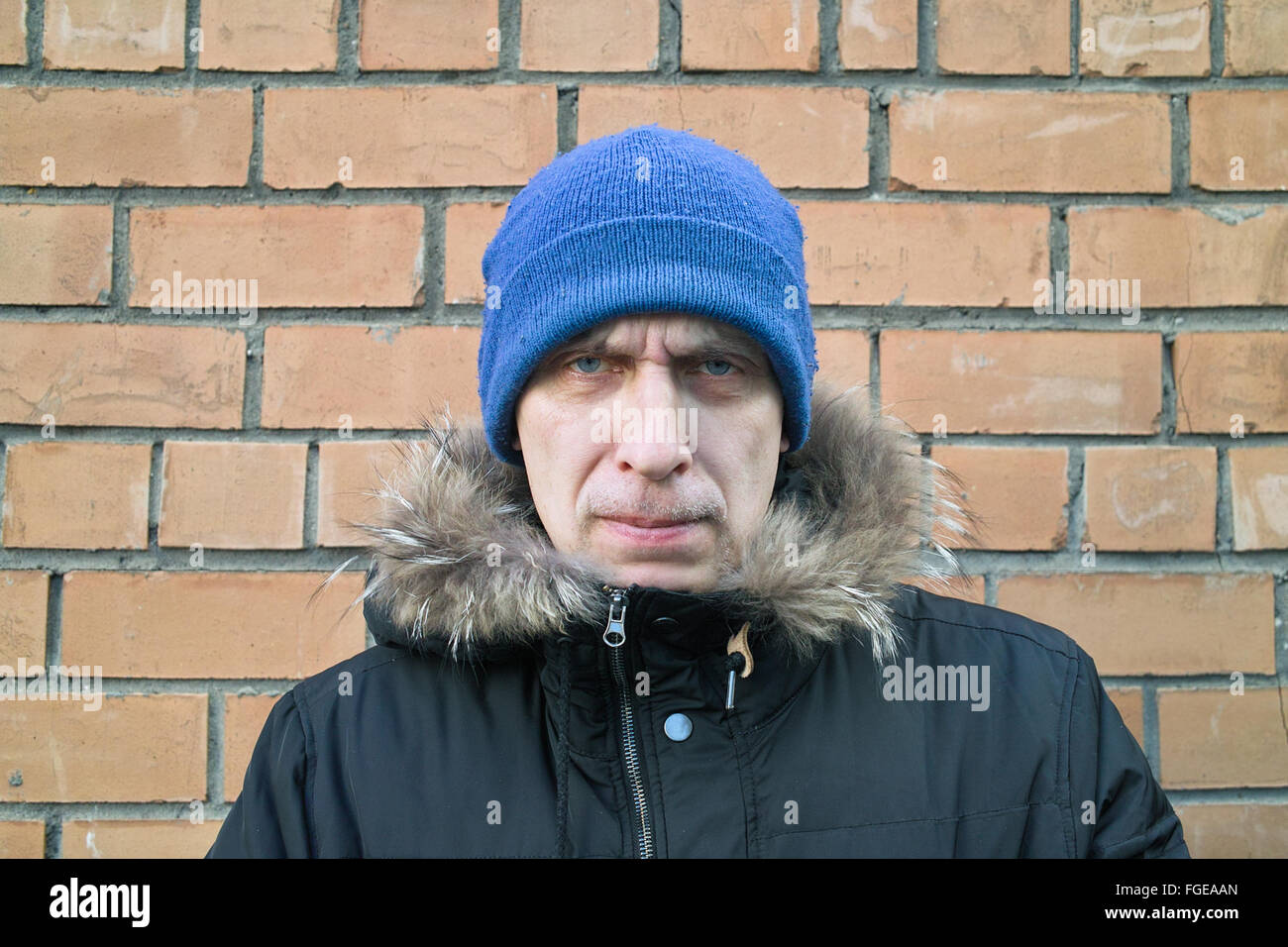 Man with a sullen look on his face posing next to a brick wall Stock ...