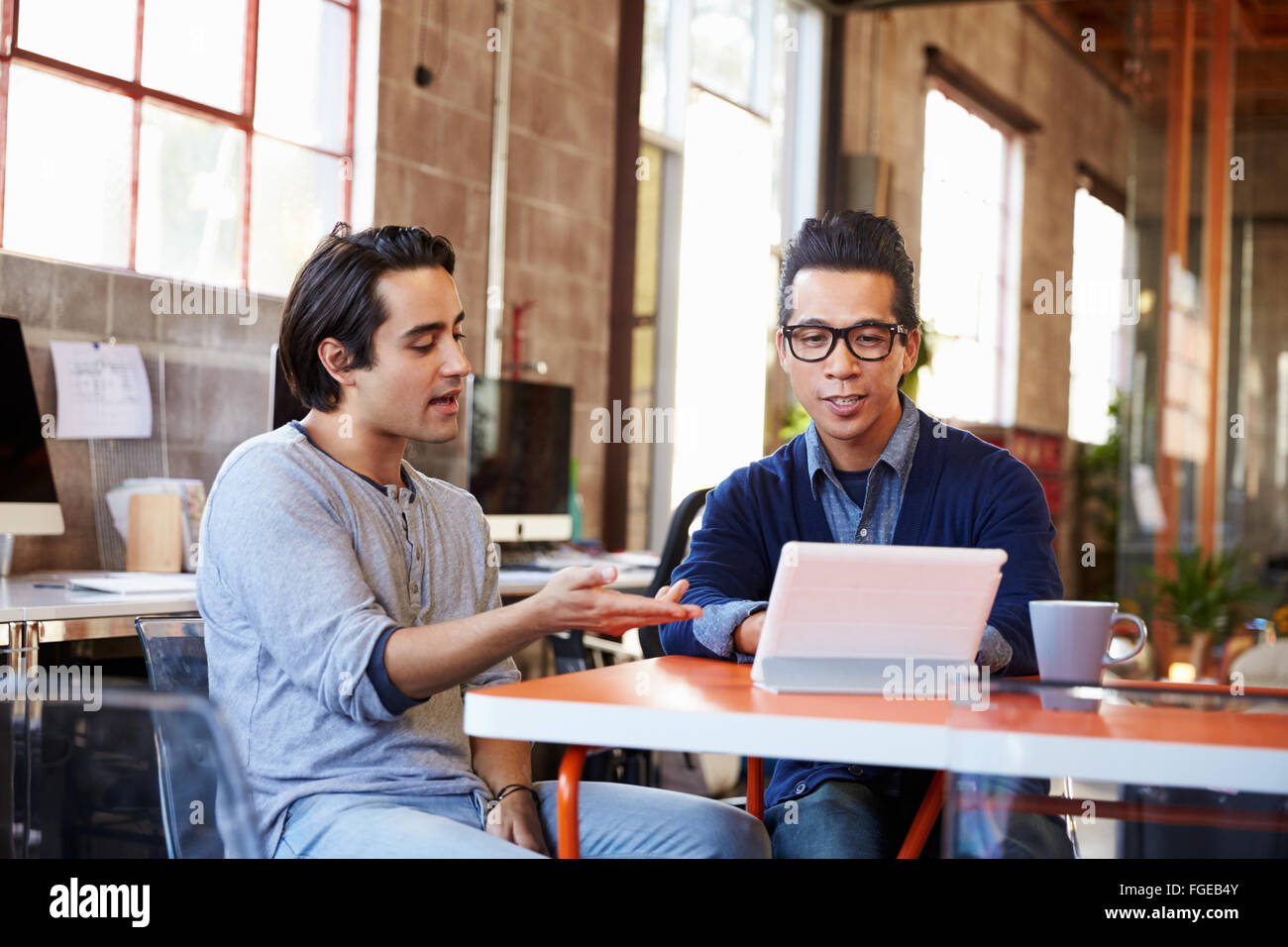 Two Designers Sit At Meeting Table Working On Digital Tablet Stock ...