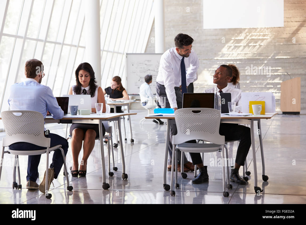 Manager Helping Staff In Busy Office Environment Stock Photo - Alamy