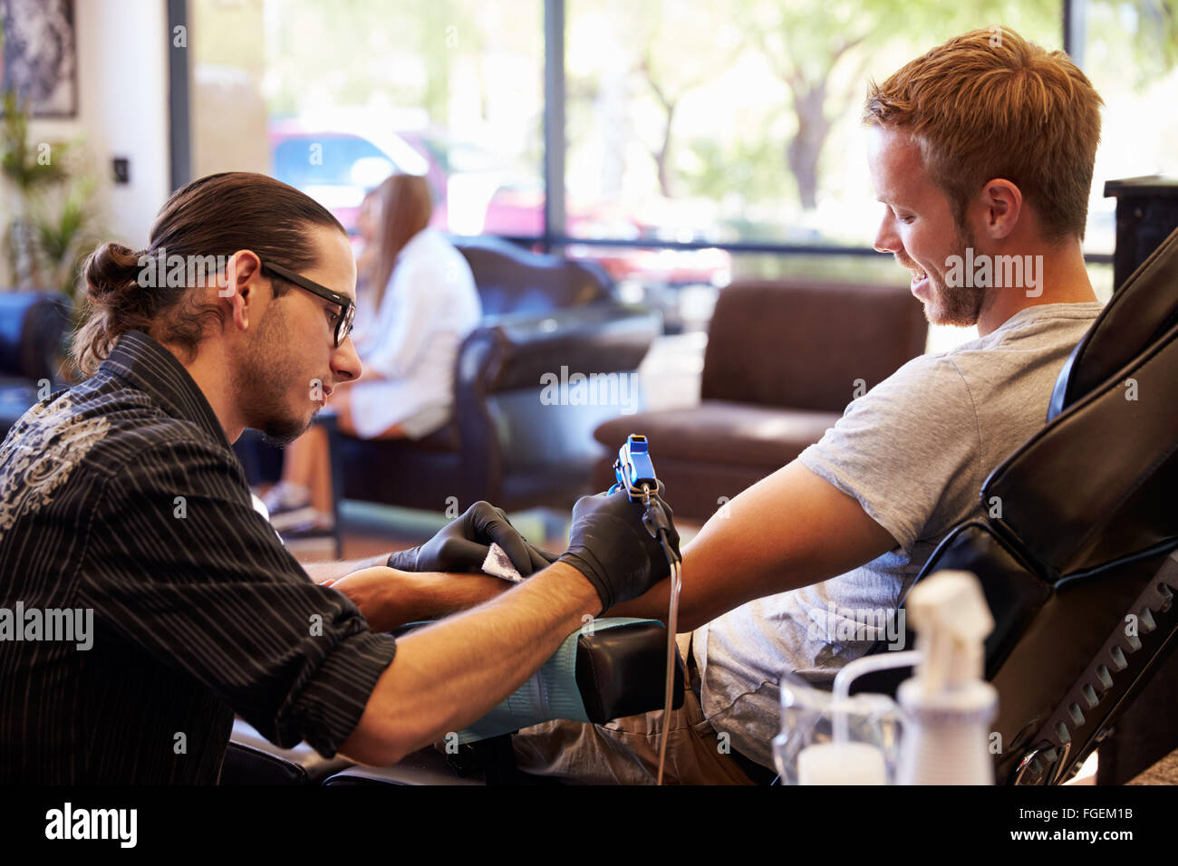 Man Sitting In Chair Having Tattoo On Arm In Parlor Stock Photo - Alamy