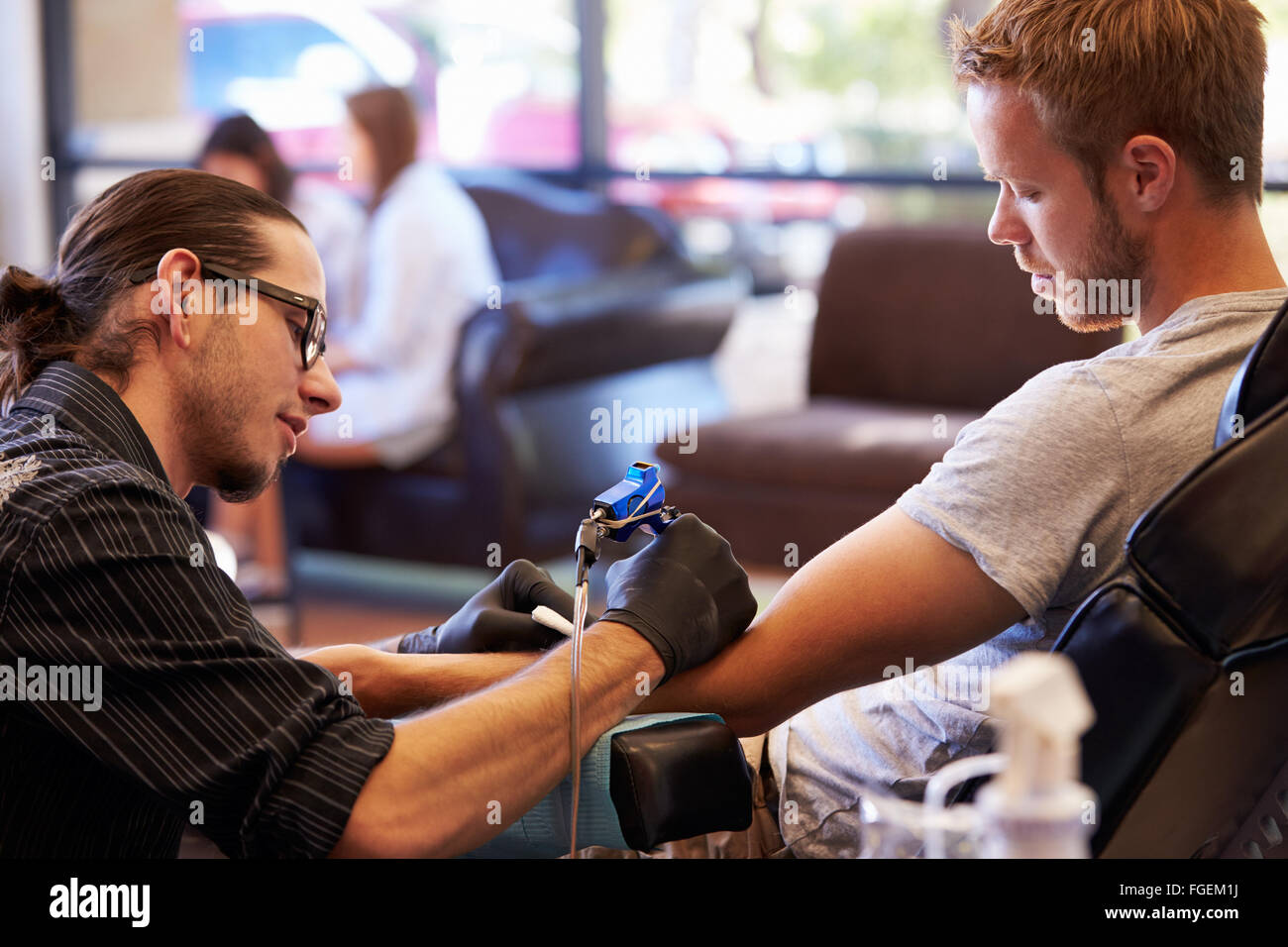 Man Sitting In Chair Having Tattoo On Arm In Parlor Stock Photo - Alamy