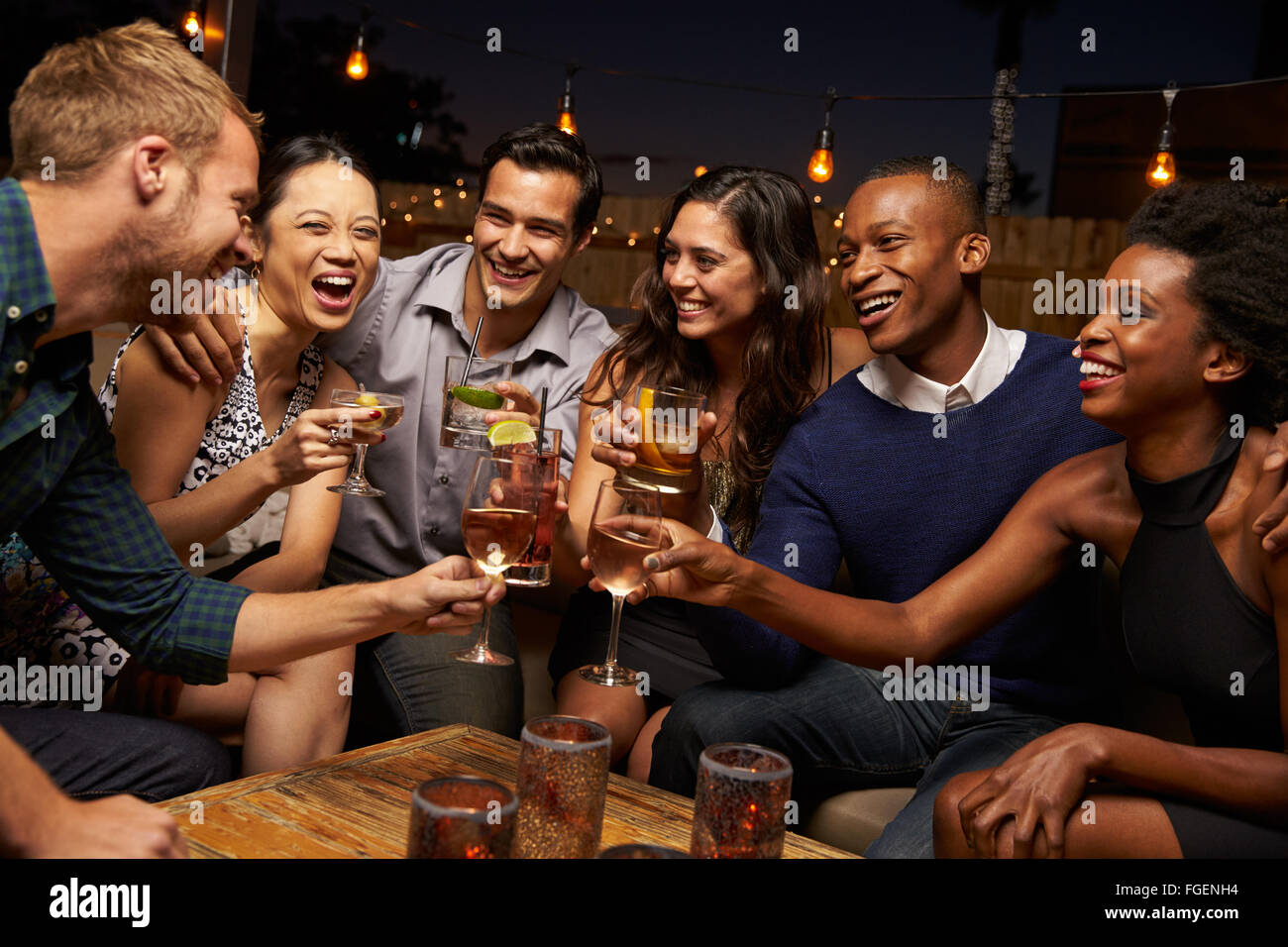 Group Of Friends Enjoying Night Out At Rooftop Bar Stock Photo - Alamy