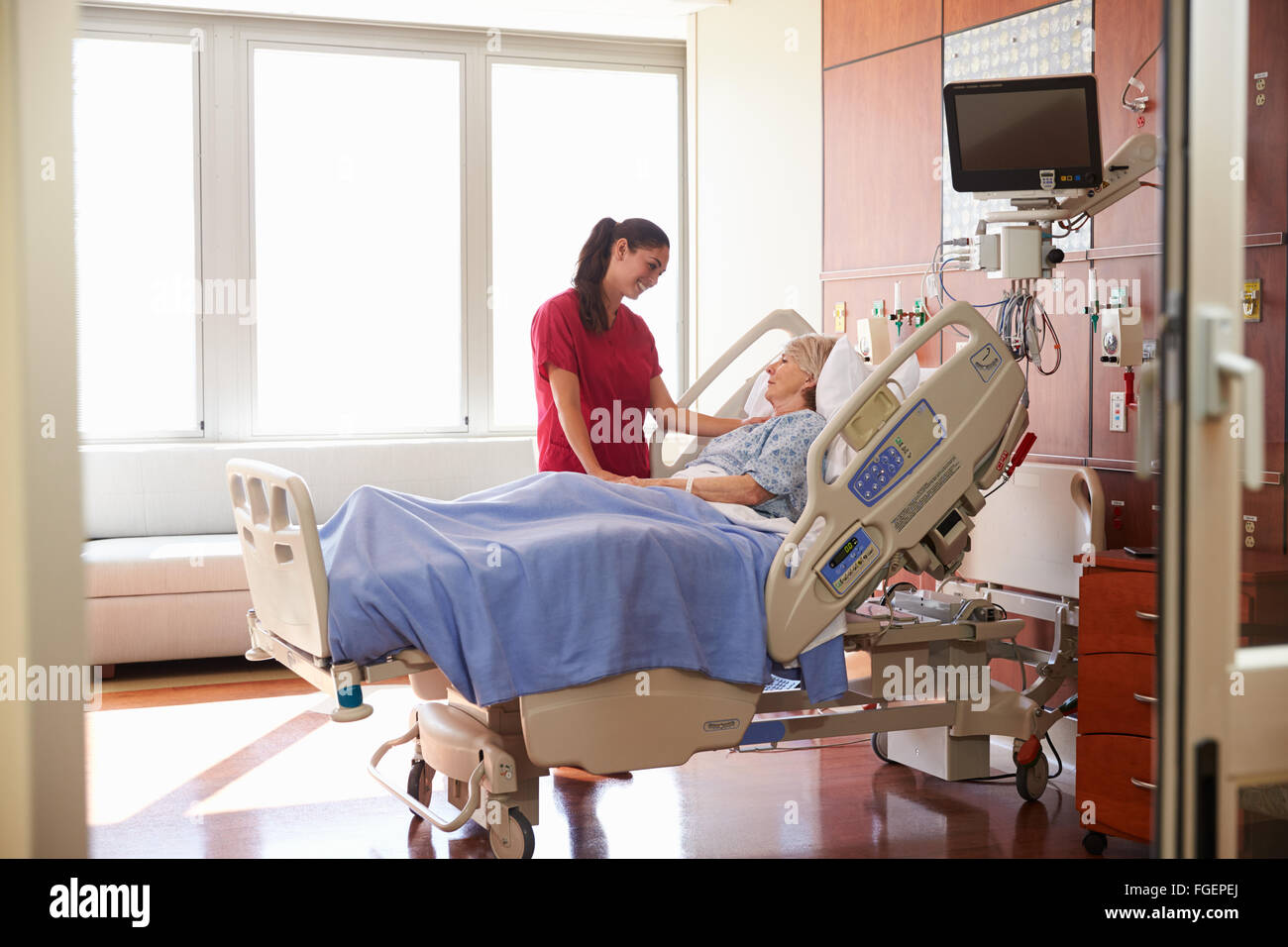 Nurse Talking To Senior Female Patient In Hospital Bed Stock Photo - Alamy
