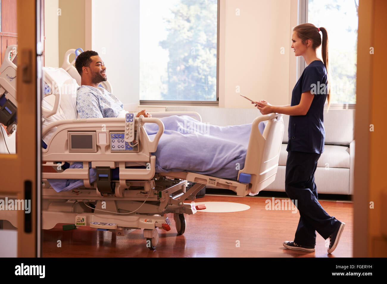 Hospital Nurse With Digital Tablet Talks To Male Patient Stock Photo ...