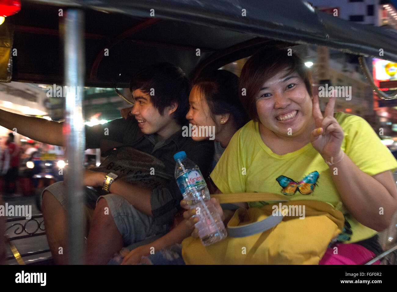 Asian tourists inside a Tuk tuks taxi in the street. View down Thanon Yaowarat road at night in ...