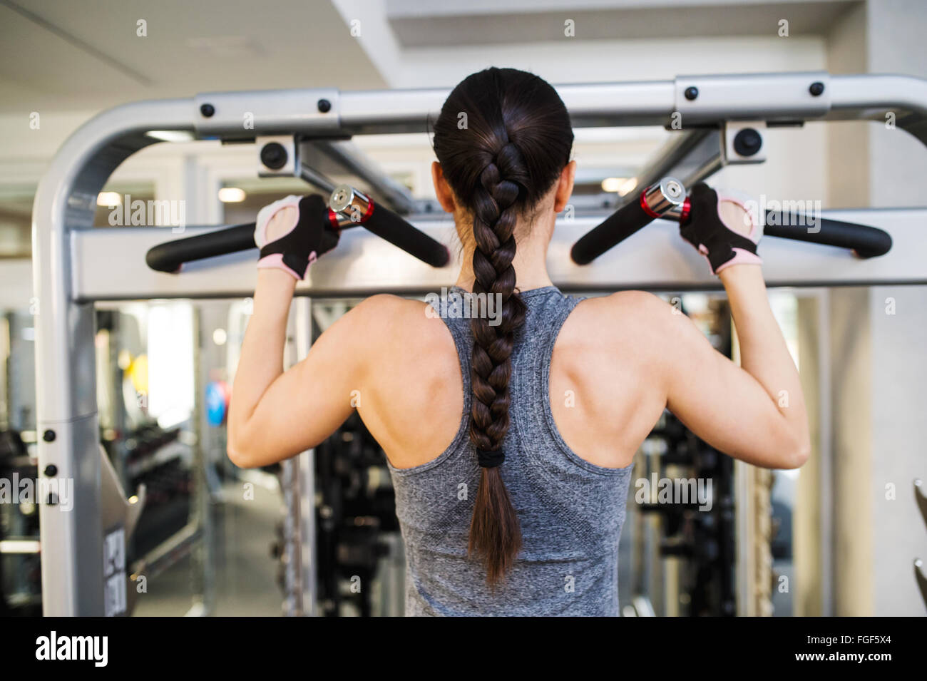 Woman in gym flexing back muscles on cable machine Stock Photo - Alamy