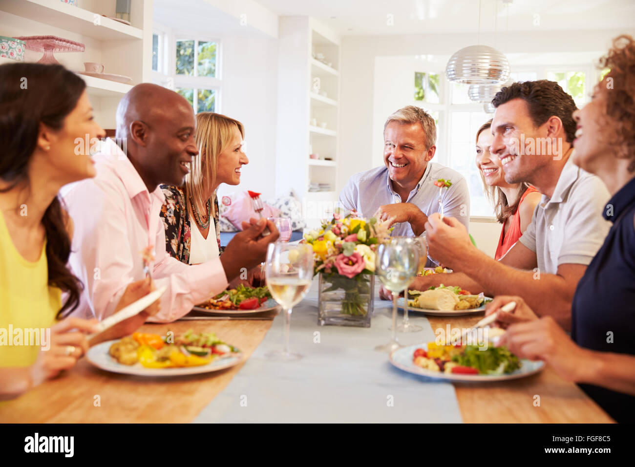 Mature Friends Sitting Around Table At Dinner Party Stock Photo - Alamy