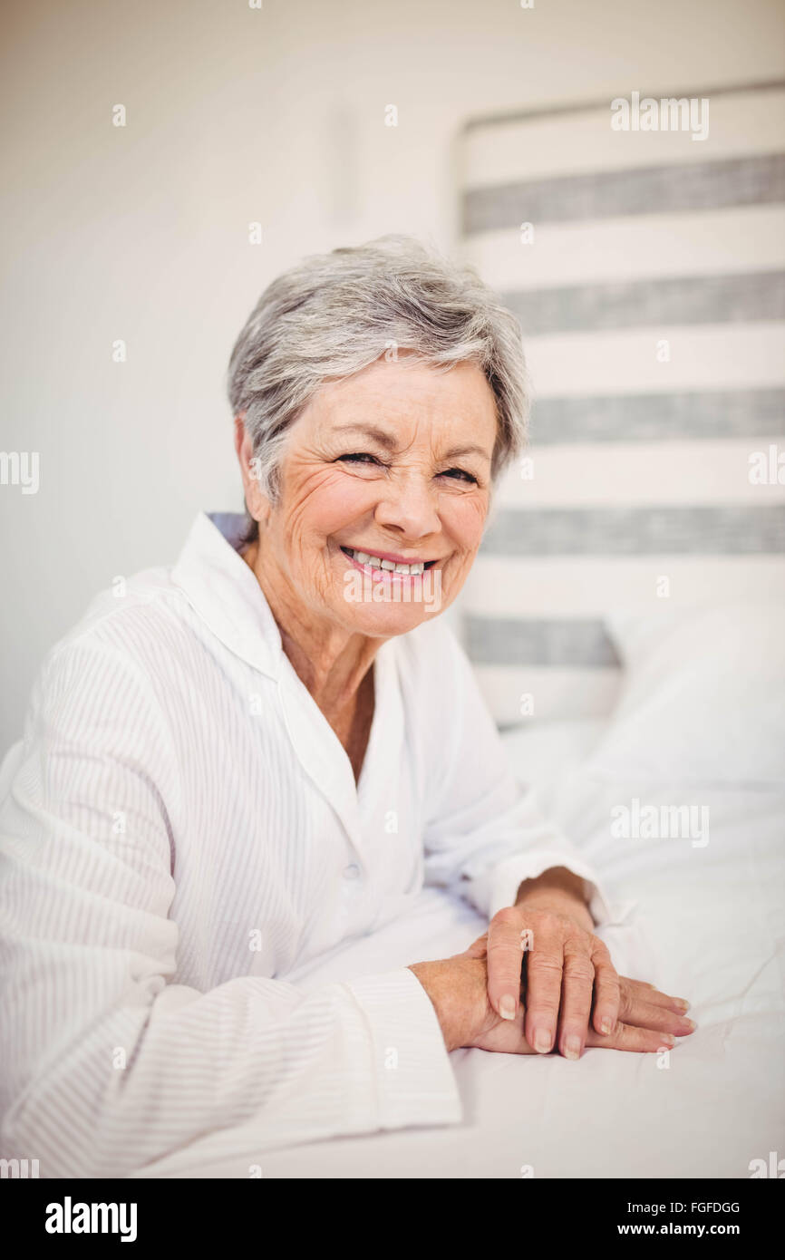 Portrait of happy senior woman sitting on bed Stock Photo - Alamy